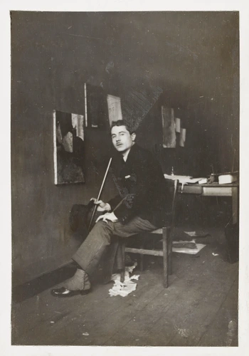 Paul Guillaume tête nue, canne et chapeau à la main droite, assis, dans ...