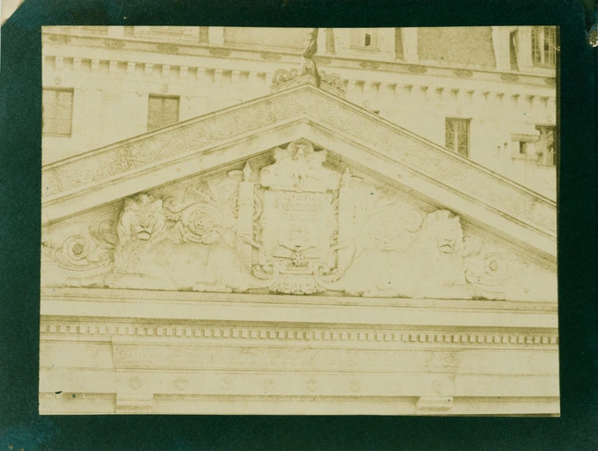 Vue d'un fronton avec deux lions et un blason contenant l'inscription ...