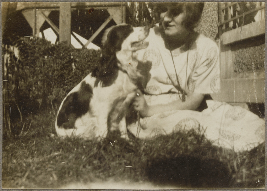 Jeune femme assise dans un jardin et tenant un chien par son collier ...